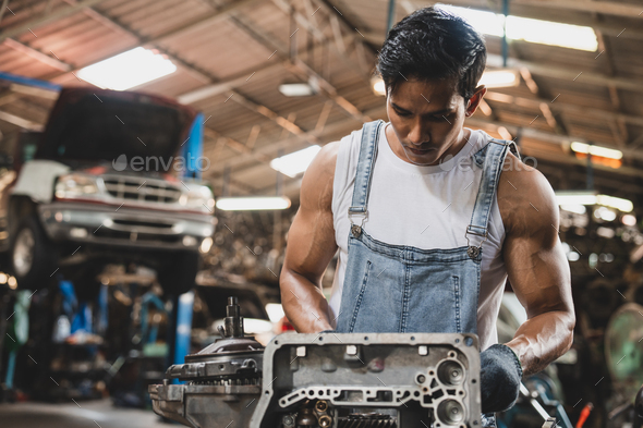 Handsome young male mechanic and car repair service man using various ...