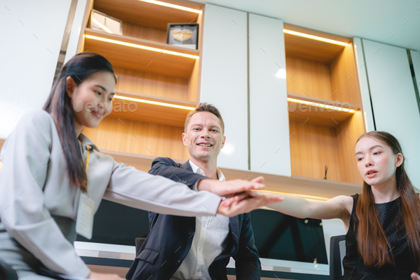 Team of young male and female employees stacking hands on top of each ...