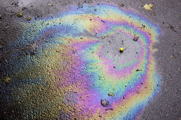 Petrol on the asphalt a big polluted puddle water. A rainbow slick of ...