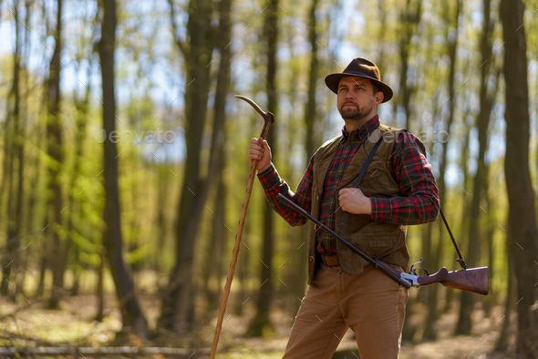 Hunter man with rifle gun on hunt in forest. Stock Photo by halfpoint