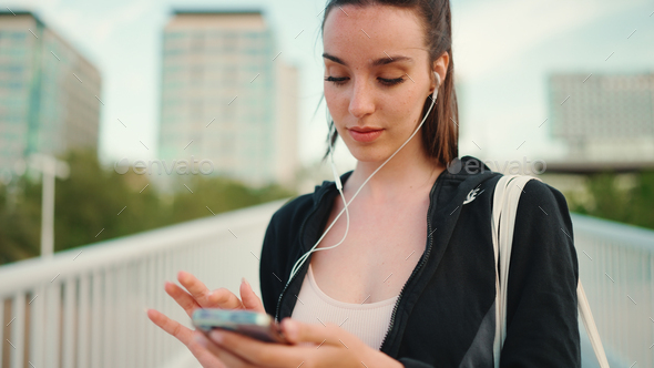 Young woman with freckles uses mobile phone and listens to music on ...