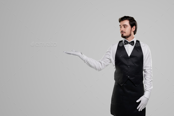 Elegant waiter pointing aside on blank space Stock Photo by kegfire