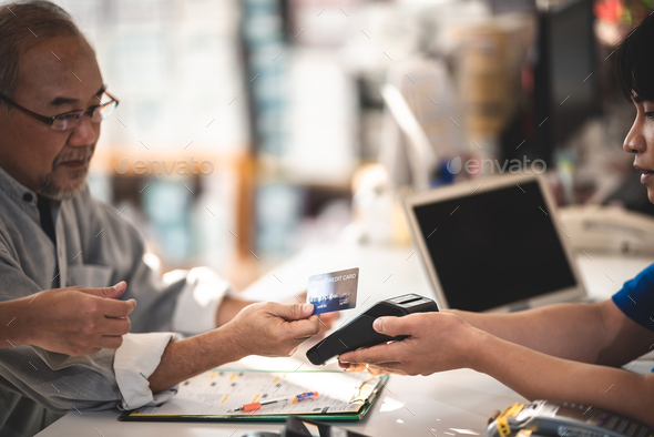 Senior customer paying garage for services and repair work using debit ...