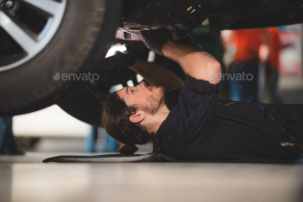 Young car mechanic and service manager in uniform and safety eyeglasses ...