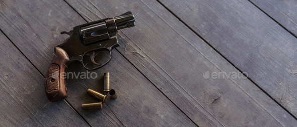 Revolver with bullets on the wooden table. Stock Photo by halfpoint