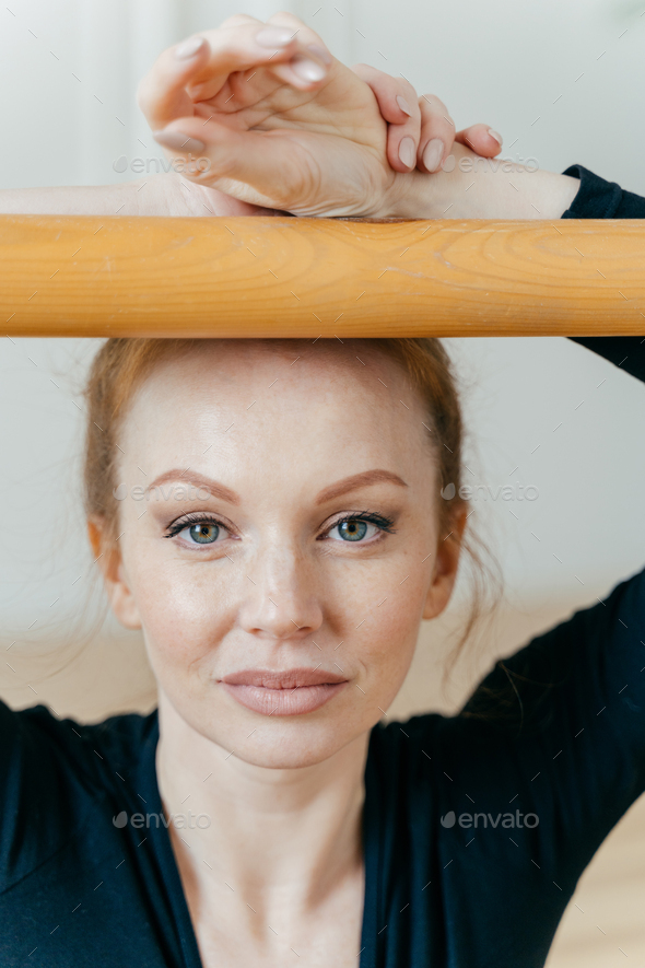 Headshot of talented skilled female ballet dancer poses near barre, has ...