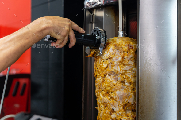 Kebab restaurant, the chef uses the electric tool to cut doner meat ...