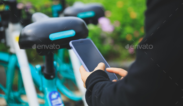 Hands using smartphone scanning the QR code of shared bike in city ...