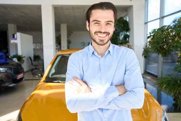 Happy new vehicle owner is posing for camera in showroom Stock Photo by ...