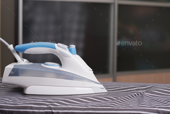 Modern iron on the ironing board, close up Stock Photo by Lazy_Bear
