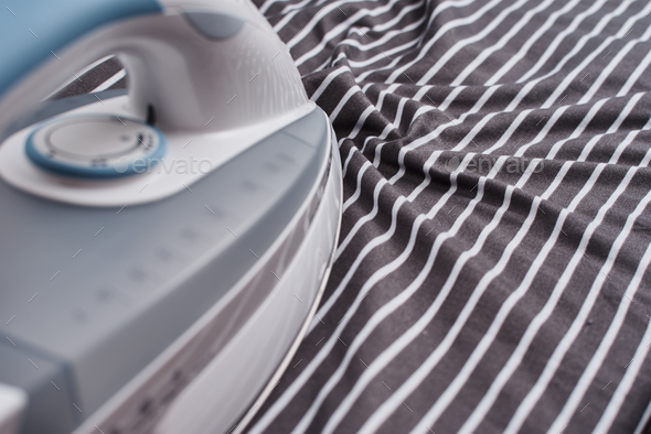 Modern iron on the ironing board, close up Stock Photo by Lazy_Bear
