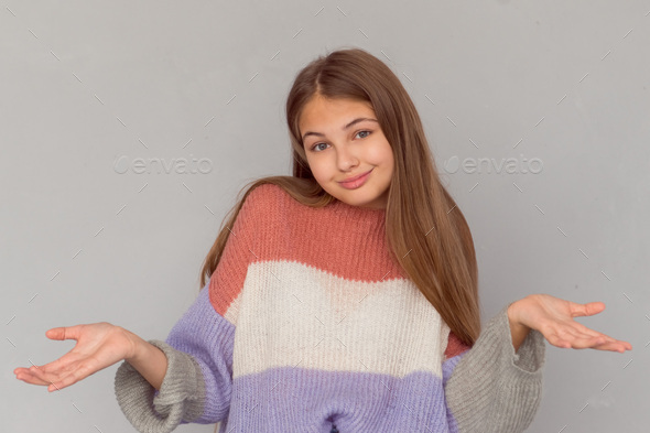 Young beautiful teen girl making shrugging shoulders isolated on grey ...