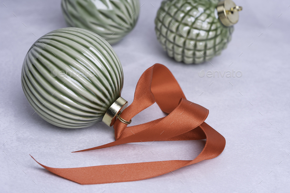 Christmas ceramic bauble with an untied ribbon on a light background ...