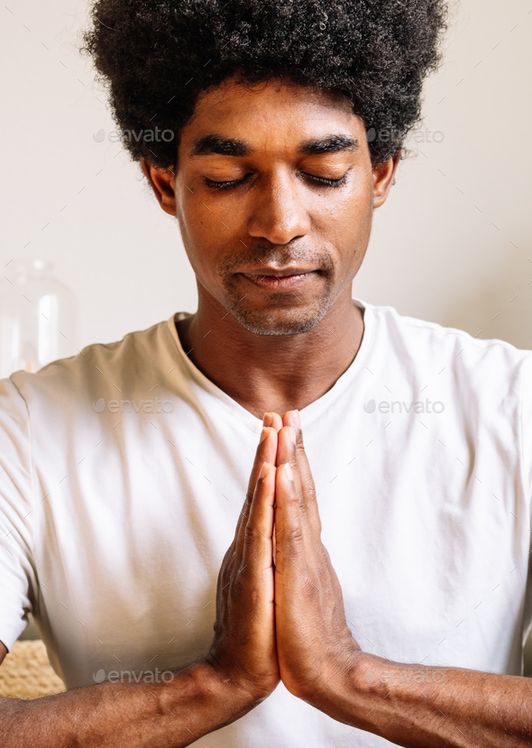 Detail of an afro man meditating with his hands clasped on his chest ...