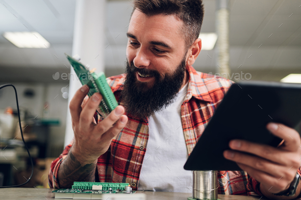 Electronics engineer working in a workshop while holding tablet and ...
