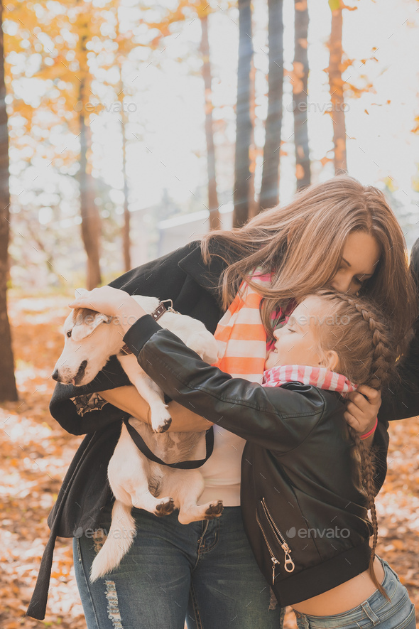 Mother and daughter in autumn park, girl hugging her jack russell ...