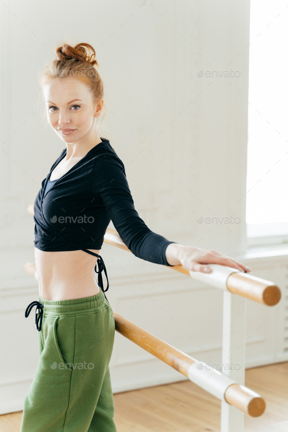 slim young female dancer stands back to barres, demonstrates dancing ...