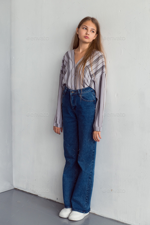 beautiful teen girl model wearing jeans and blouse posing at neutral ...