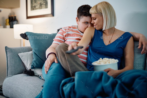 Female couple in love watching movies on TV while relaxing at home ...