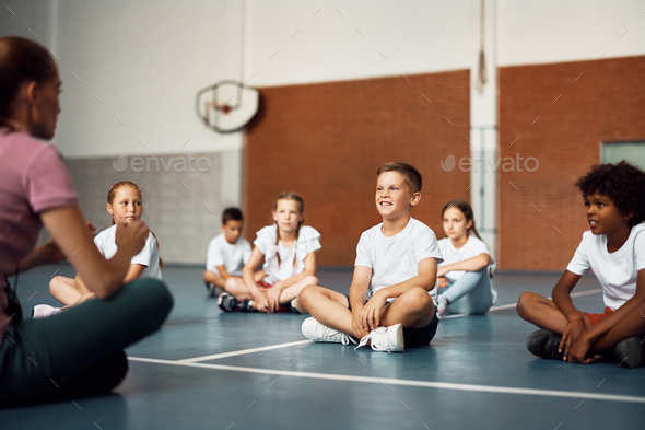 Happy elementary student and his classmates having PE class with female ...