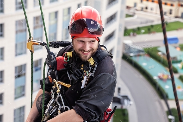 Industrial mountaineering worker in uniform during high-rise work ...
