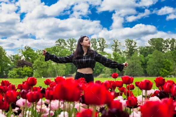 Portrait teenage girl walking in spring park with colorful flowers ...