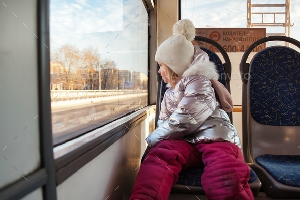 Little girl in bus watching at window of public city transport. Child ...