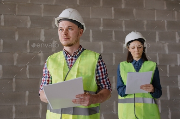 two engineers, a man and a woman in white helmets and protective signal ...