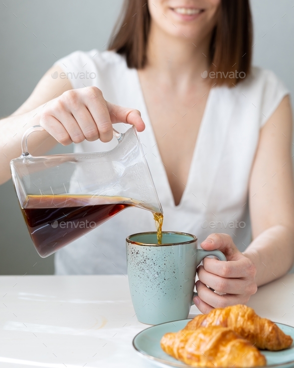 Caucasian woman pours a filter or Americano into a cup of black coffee ...