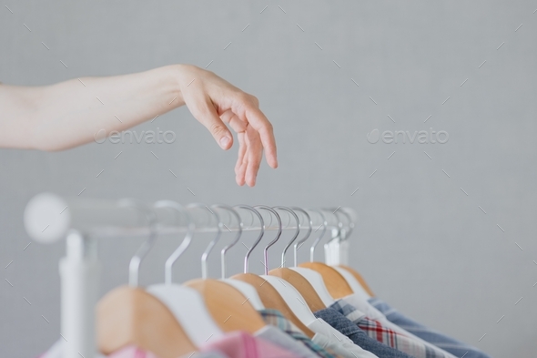 woman's hand and clothes rack, white woman chooses a shirt or dress for ...