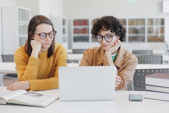 two European female students or researchers are reading a book in a ...