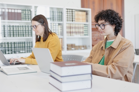 two European female students or researchers are reading a book in a ...