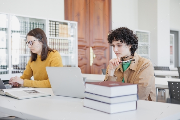 female students or researchers are reading a book in a library or ...