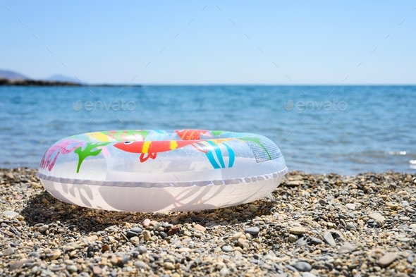 inflatable swimming children circle lies on the pebble beach on the ...