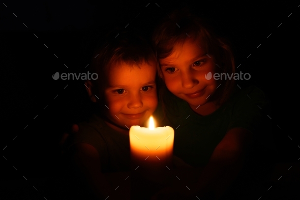 happy laughing kids siblings boy and girl admires a burning wax candle ...