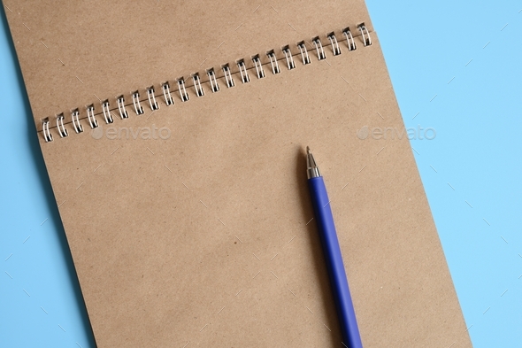 notebook or sketchbook made of craft paper and a pen on a blue ...