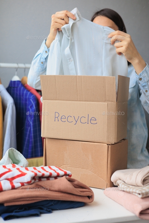woman puts clothes in a box for recycling. garbage sorting and eco ...