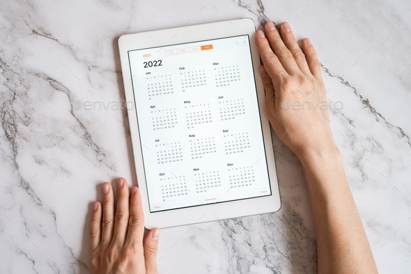 tablet computer with calendar for 2022 year, hands holding. flat lay ...