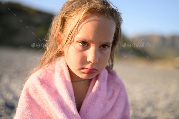 sad six year old little girl resting on the sea beach after swimming ...