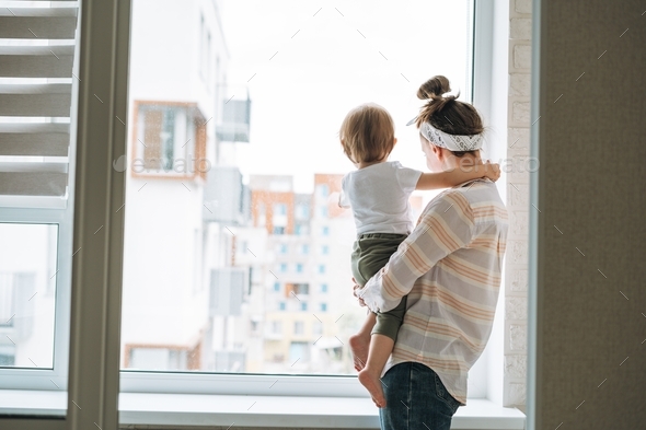 Young man father with baby girl on window sill looking at window at ...