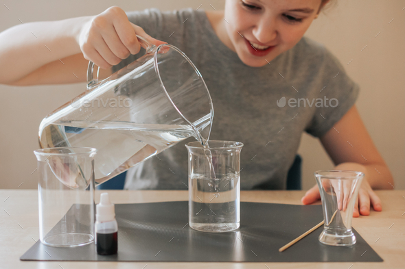 School girl filling a glass with water preparing for a science chemical ...