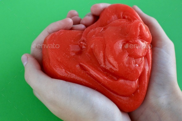 Bright red slime in children's hands on green background. Education ...