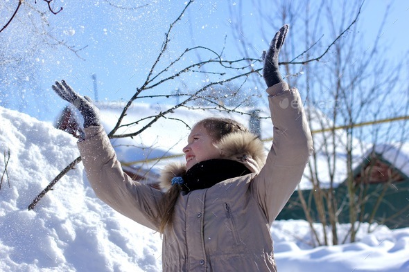 young beautiful girl throwing the snow over her head in a frosty sunny ...
