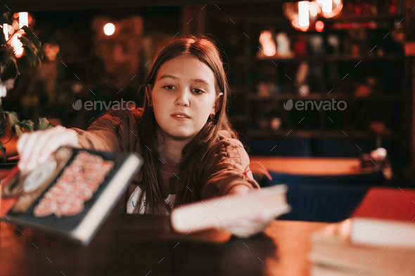 A cute teenage girl taking book to read in cafe. Education, leisure ...