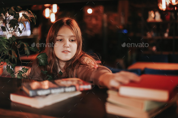 A cute teenage girl taking book to read in cafe. Education, leisure ...