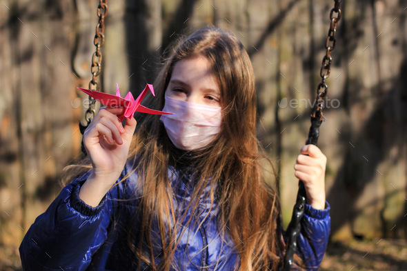 Pink and white origami paper cranes in the hands of a teenage girl in a ...