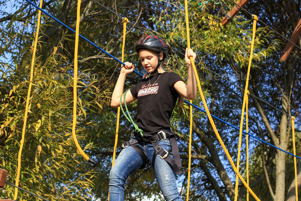 Girl in safety equipment hiking in the rope park. Climbing adventure ...
