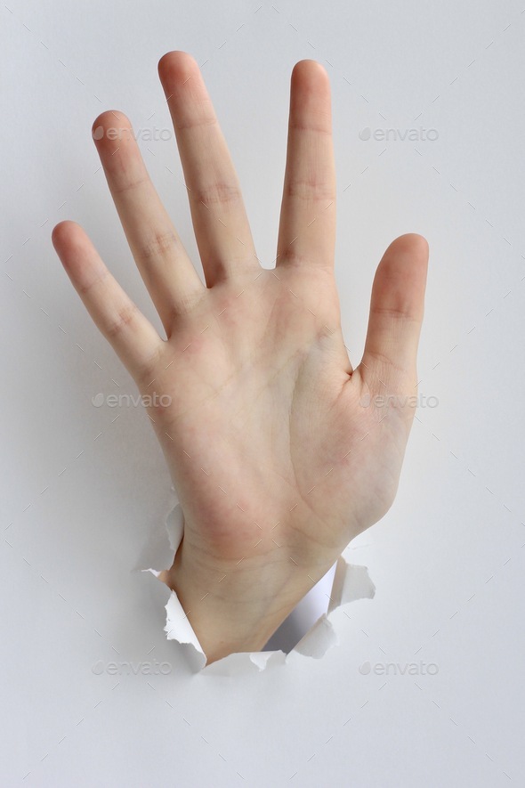 Hand showing stop gesture through a hole in paper. Gestures, signs and ...