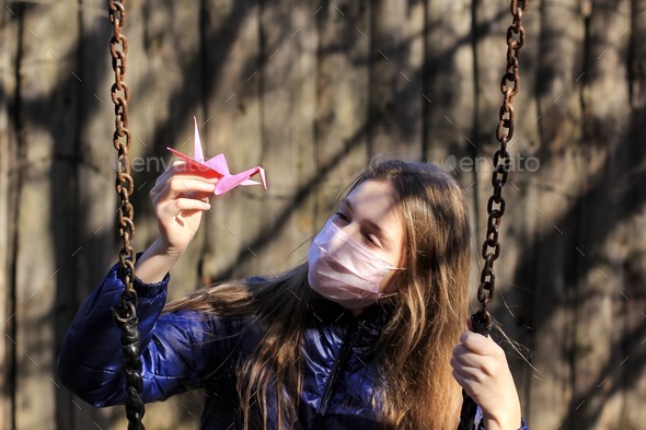 pink origami crane in the hands of a teenage girl in a medical ...