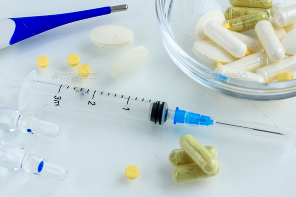 Multicolored pills, tablets against the virus, flu, disease and a glass ...